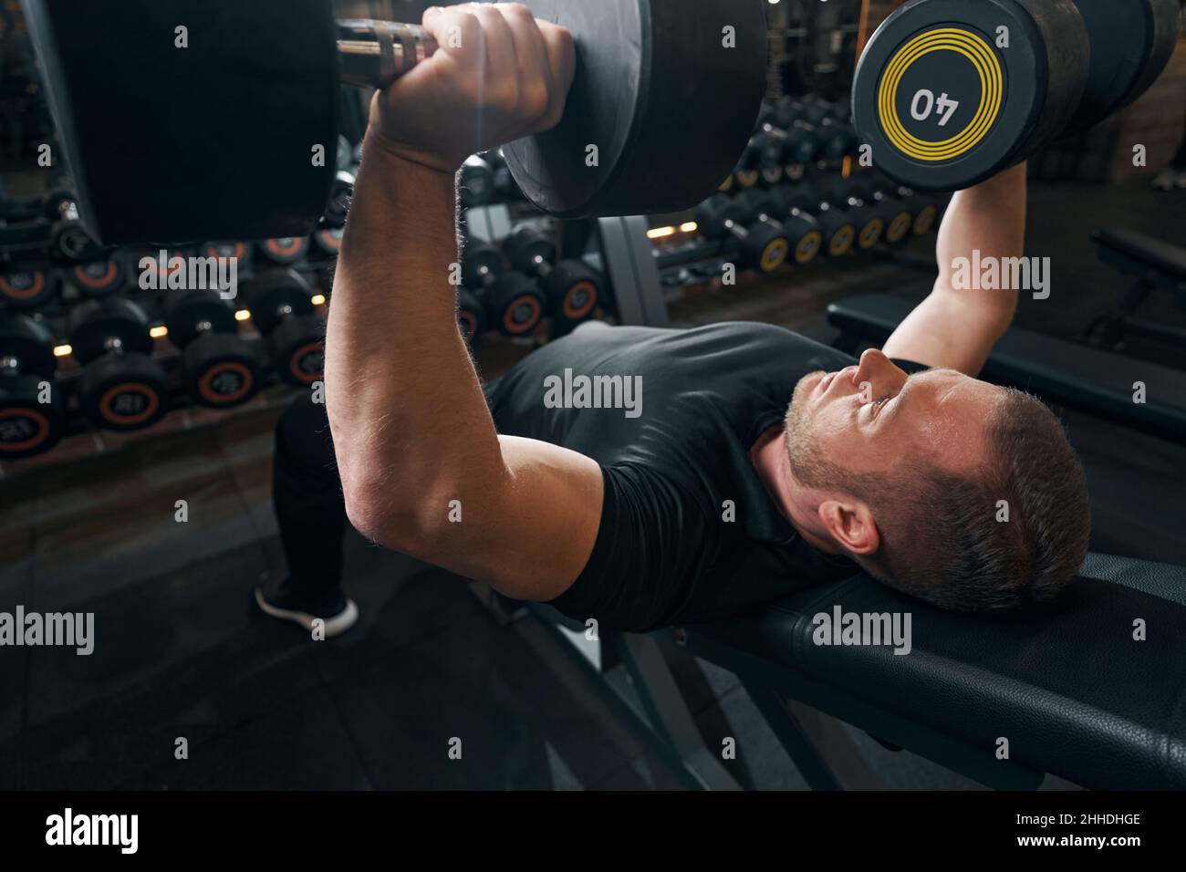 Serious male weightlifter doing upper-body weight-training exercise ...