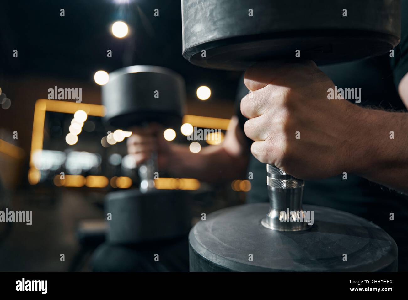 Weightlifter with hand weights seated at gym Stock Photo - Alamy