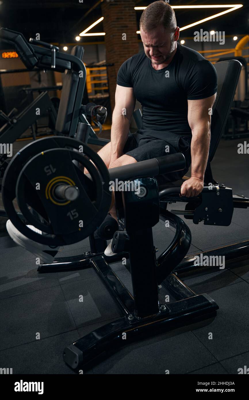 Bodybuilder doing strength-training exercise using fitness equipment ...