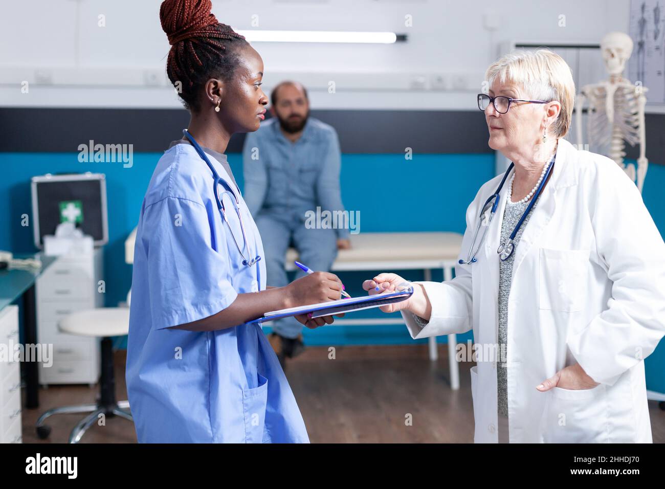 Multi ethnic medical team taking notes on clipboard about healthcare of ...