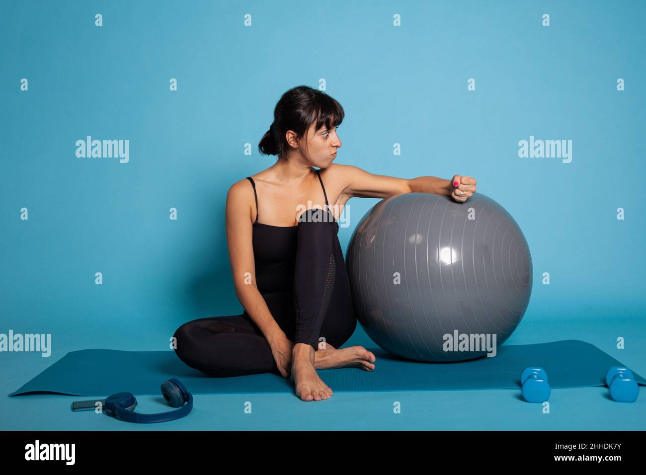 Upset sad athlete woman leaning on fitness fitball looking nervous ...