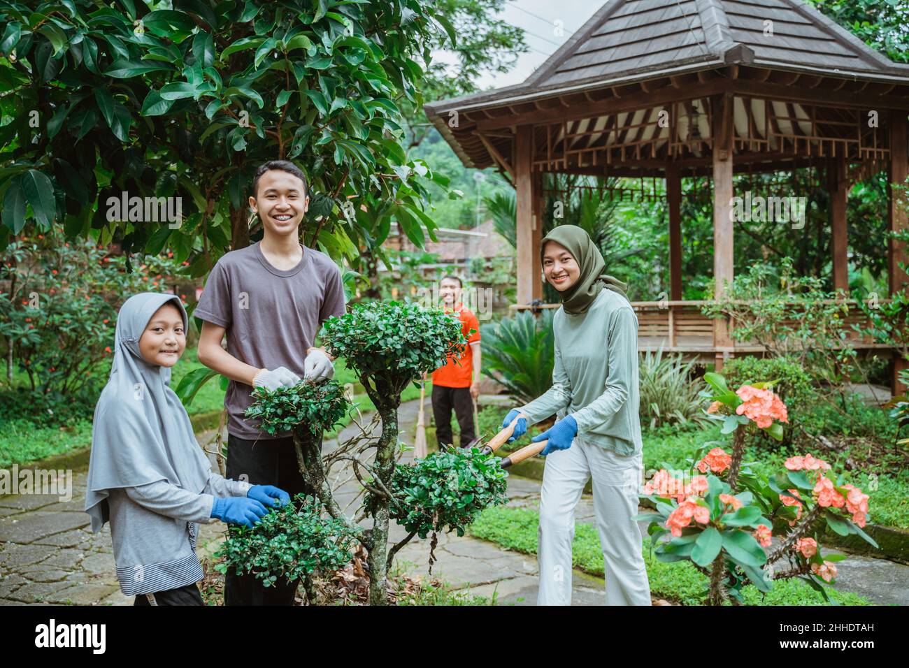 Father and mother using pruning shears with two children helping Stock ...
