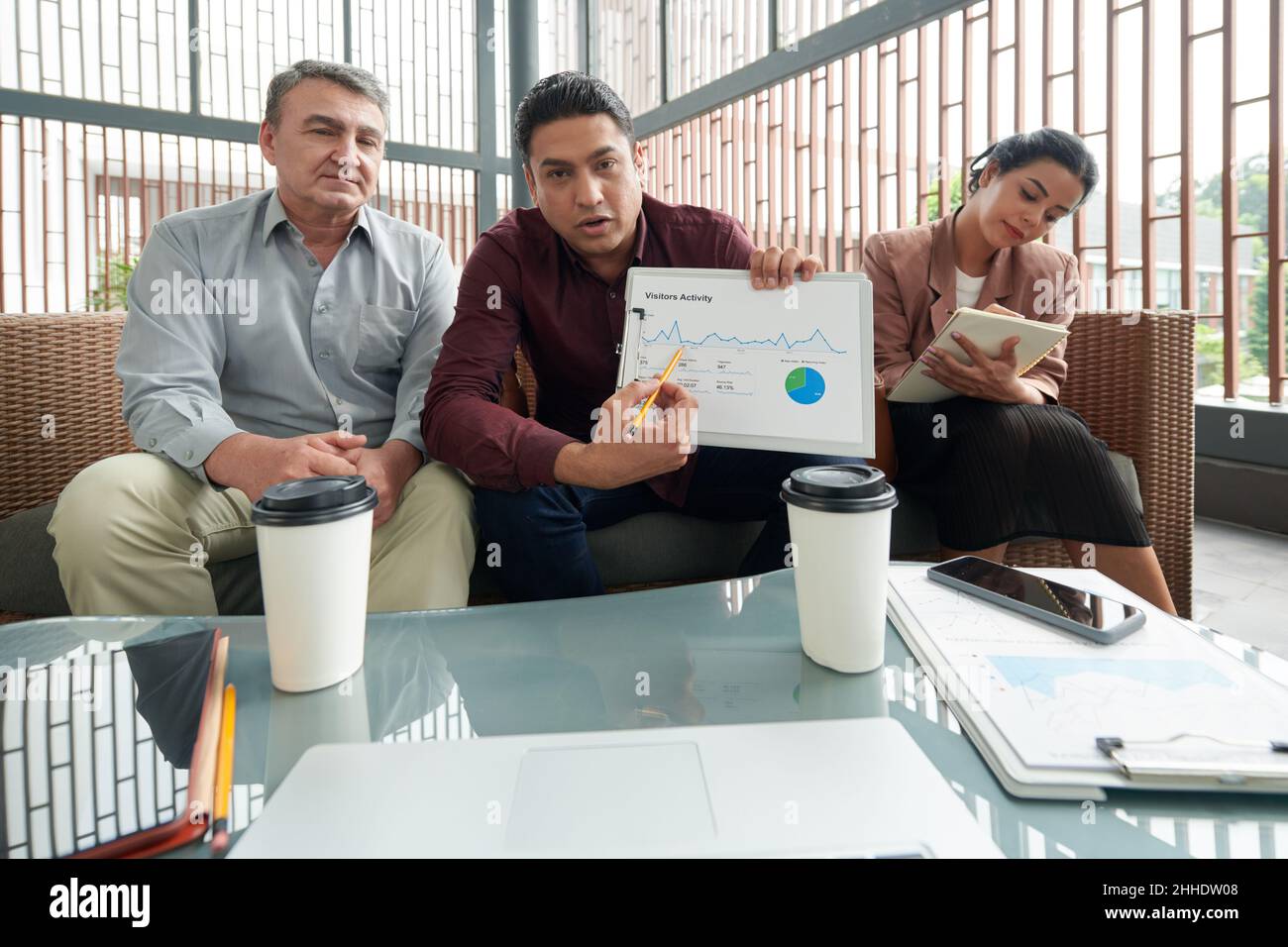 Serious businessman looking at camera and explaining details on ...