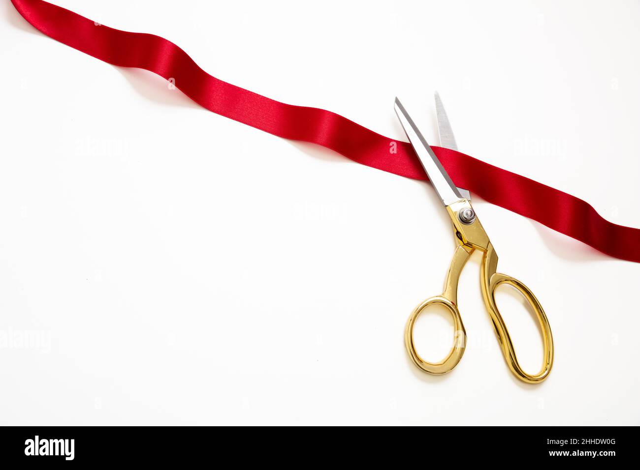 Grand opening, ribbon cut, Gold scissors cutting red satin ribbon ...