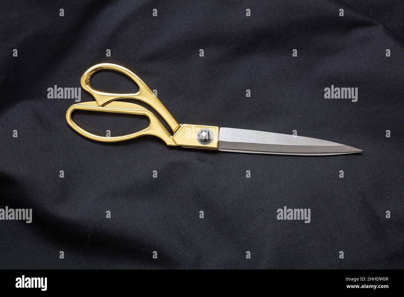 Pair of scissors gold handle on black color cloth background, top view ...