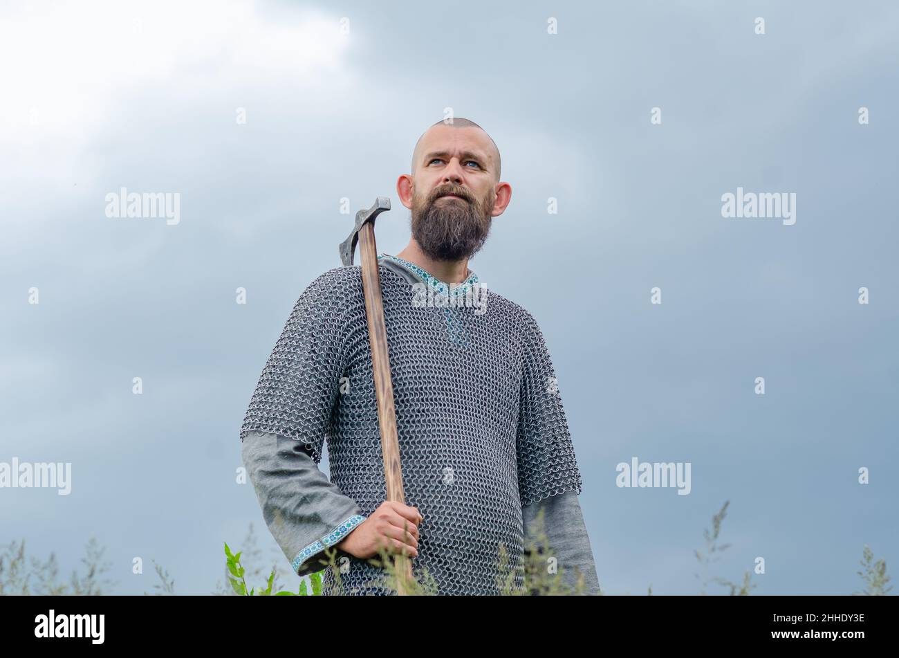 Viking. A bald bearded man in metal chain mail over linen shirt holds ...