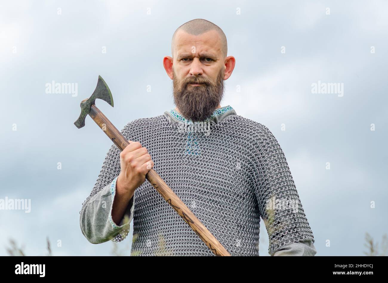 Emotional photo of medieval Viking in metal chain mail swinging ax ...