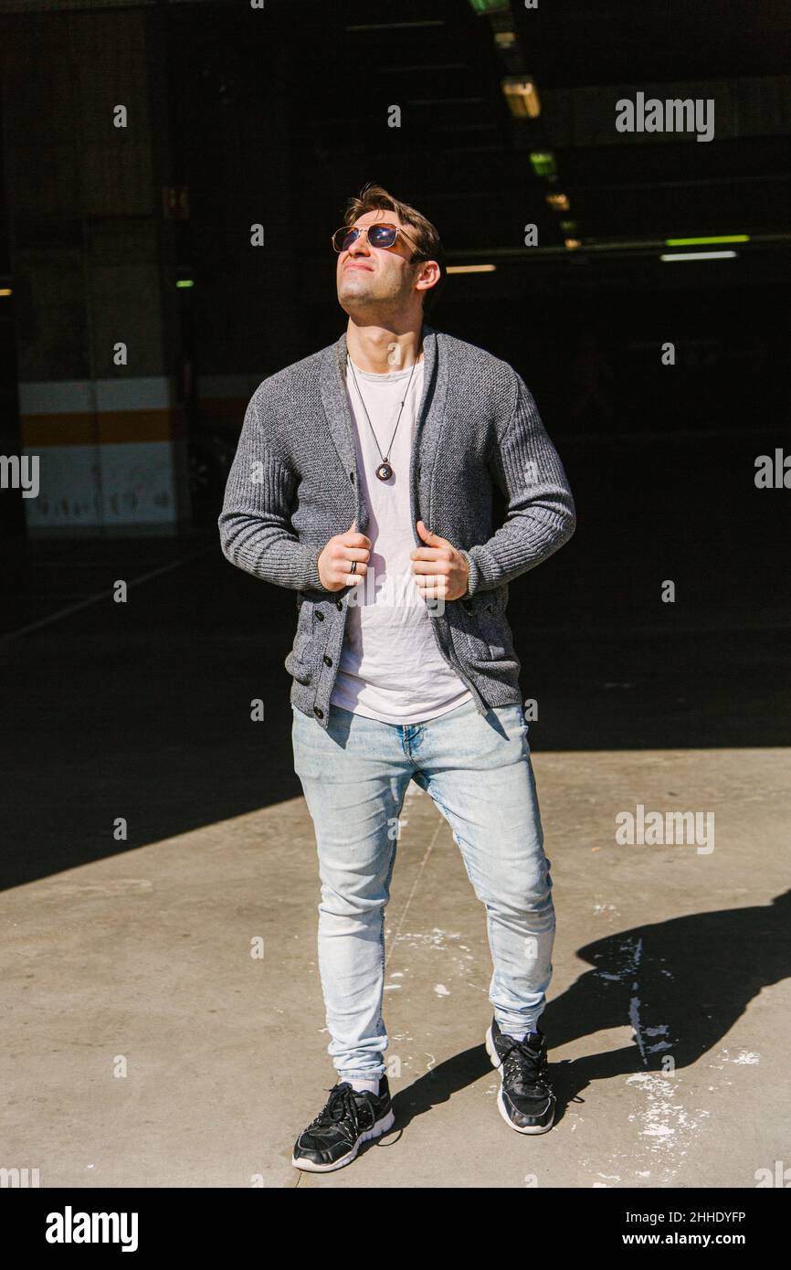 portrait of fashionable cool man walking outdoors with hands his jacket ...
