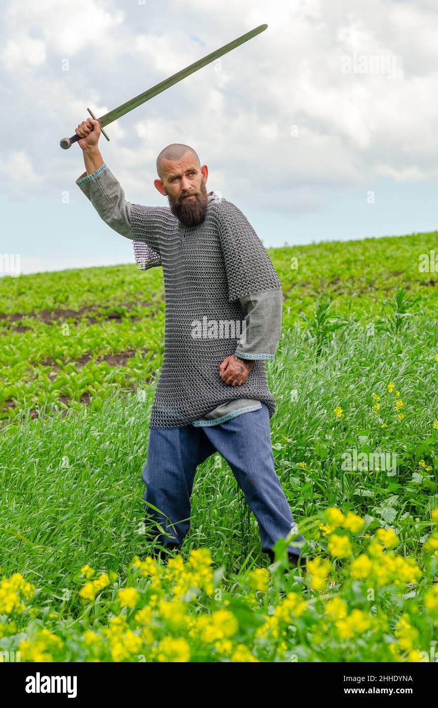 Emotional photo of medieval Viking in metal chain mail swinging sword ...