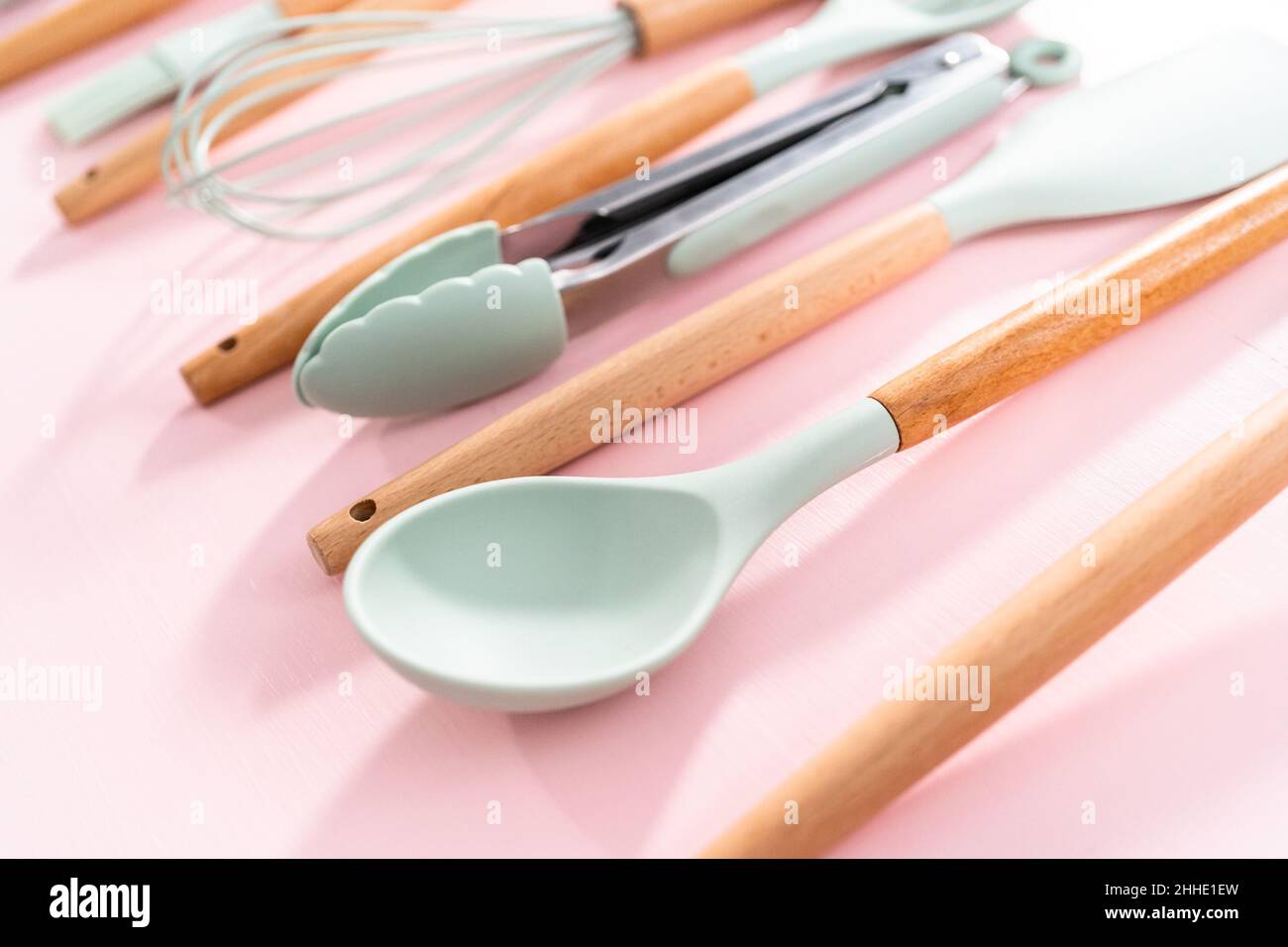 New blue silicone kitchen utensils with wooden handles on a pink ...