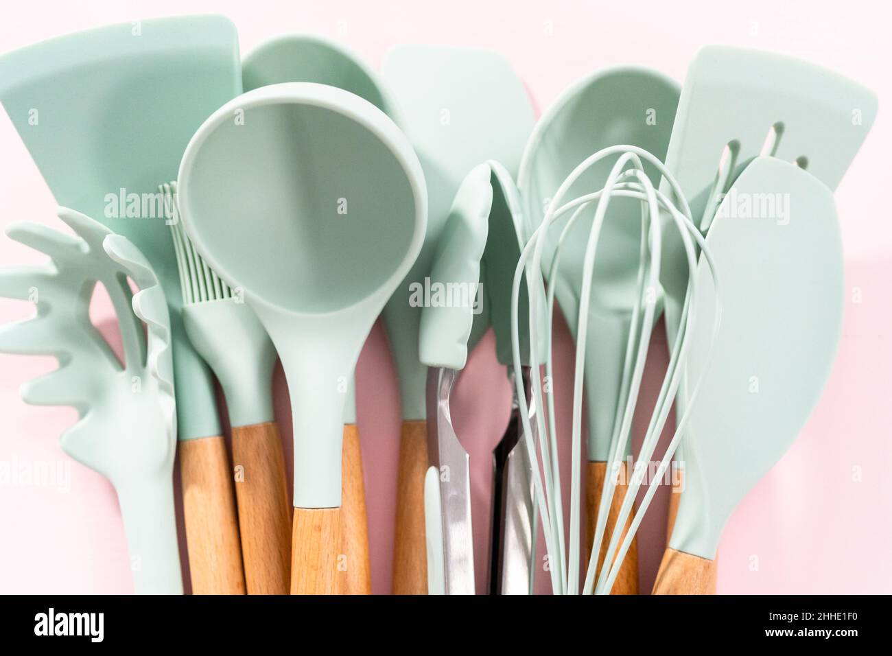 New blue silicone kitchen utensils with wooden handles on a pink ...