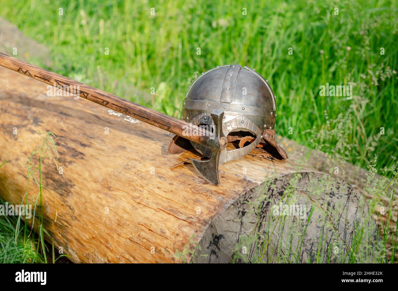 View of ancient Viking armor lying on a wooden log. Helmet and ax ...