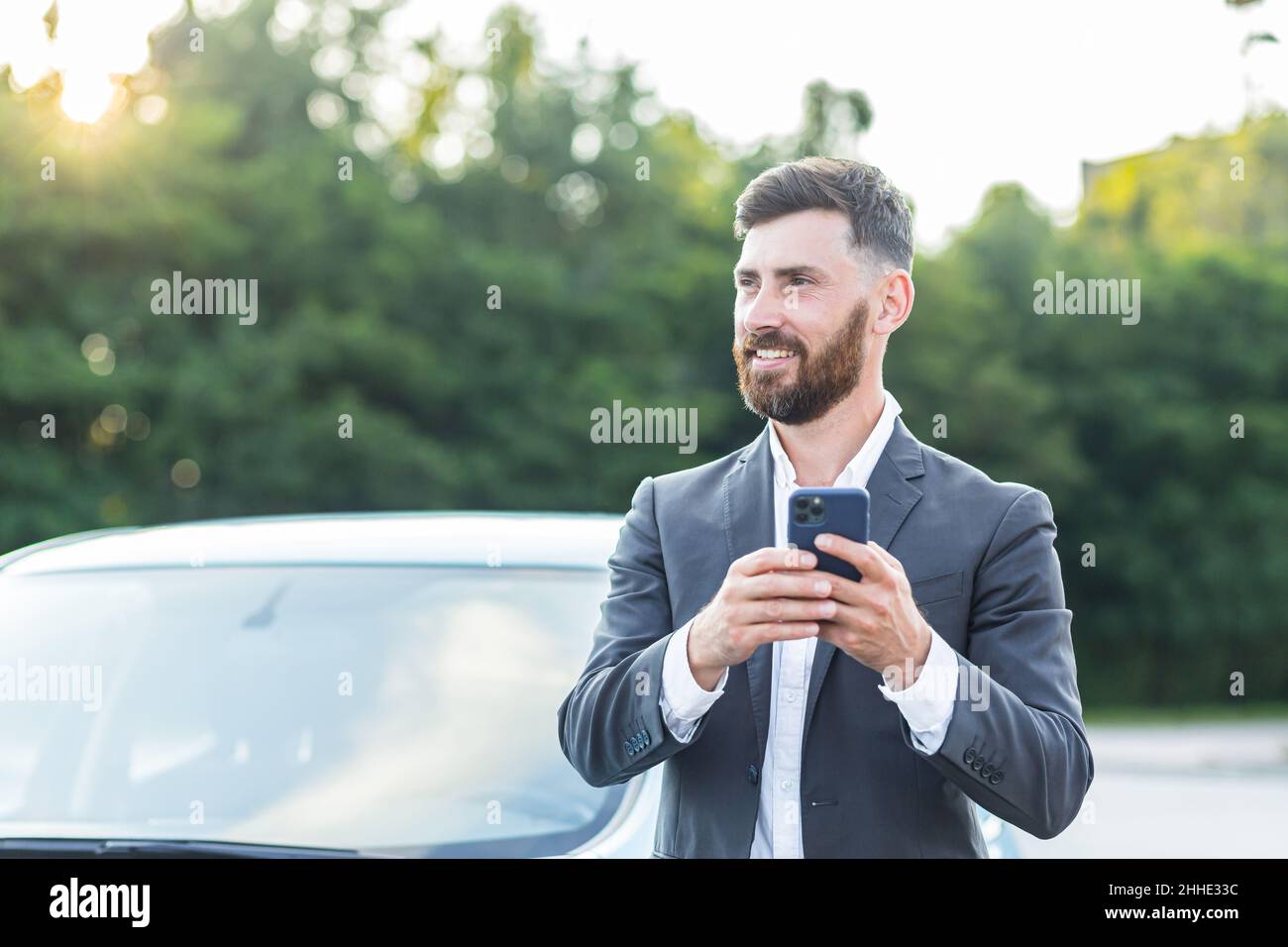 Cheerful and successful male businessman car salesman uses the phone ...