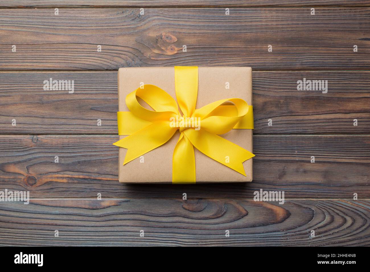 Holiday gift box wrapped in craft paper with colored bow on table ...