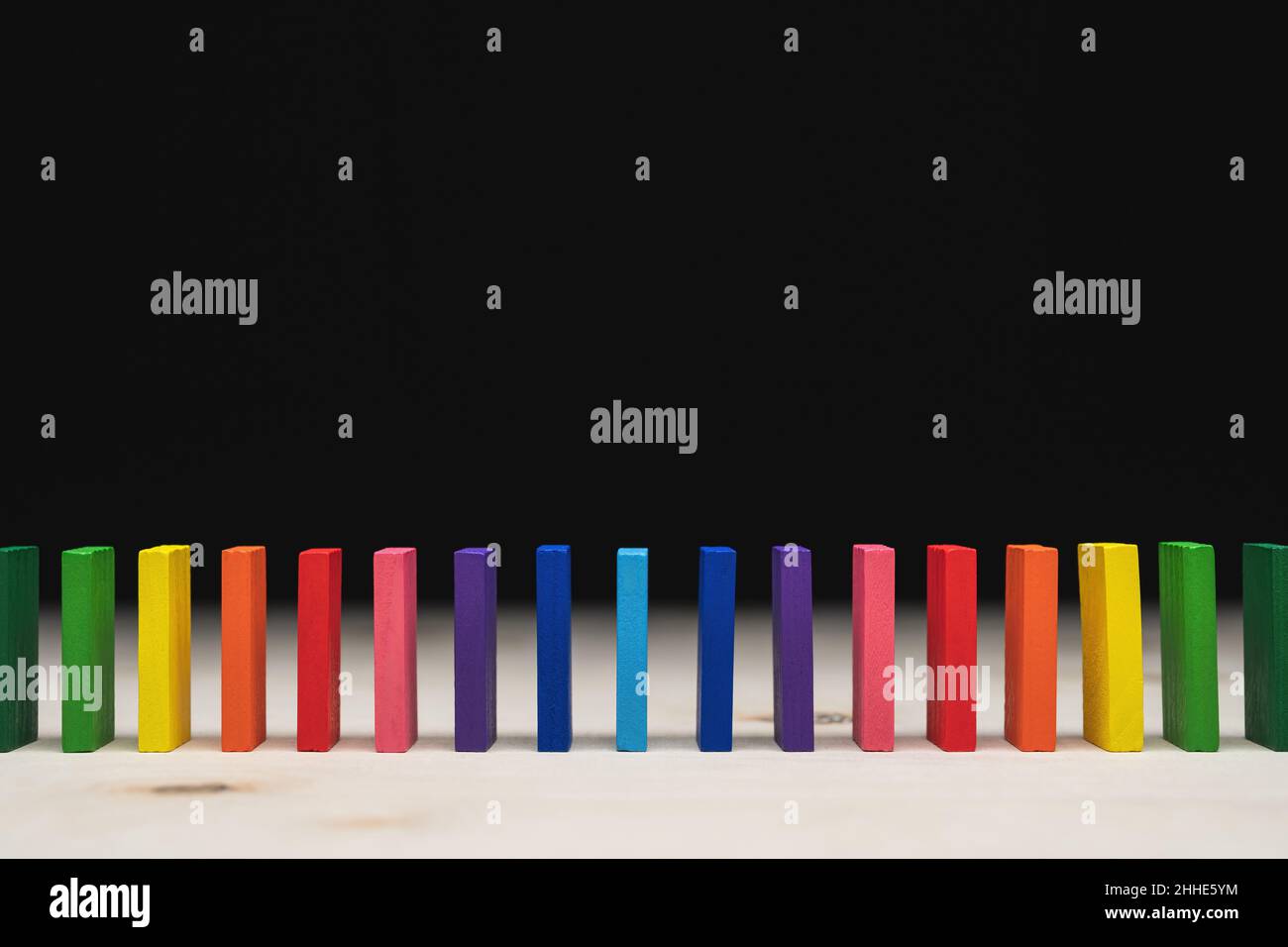 Colored dominoes lined up in a row by rainbow color. Light foreground ...