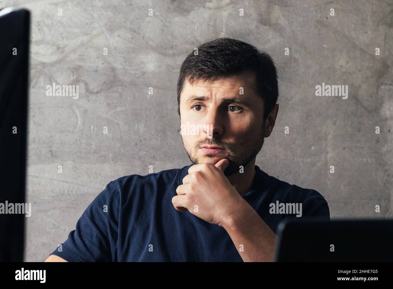 Handsome sad serious bearded man with hand at his chin sitting at the ...