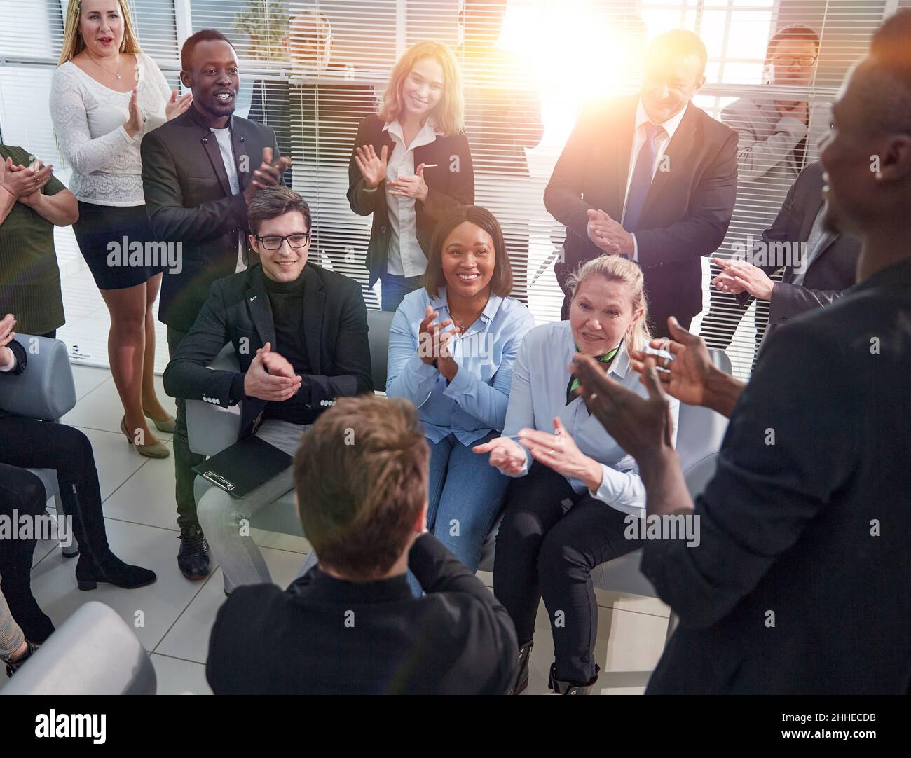 Office employees sit on chairs clap hands greeting presenter or speaker ...