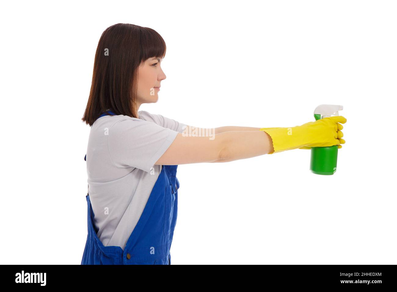 side view of young female cleaner in blue uniform holding detergent ...