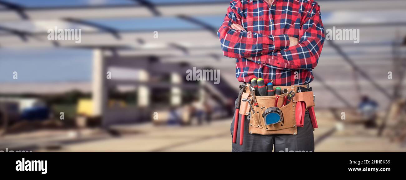 Building worker with tool belt and wood board on a construction site ...