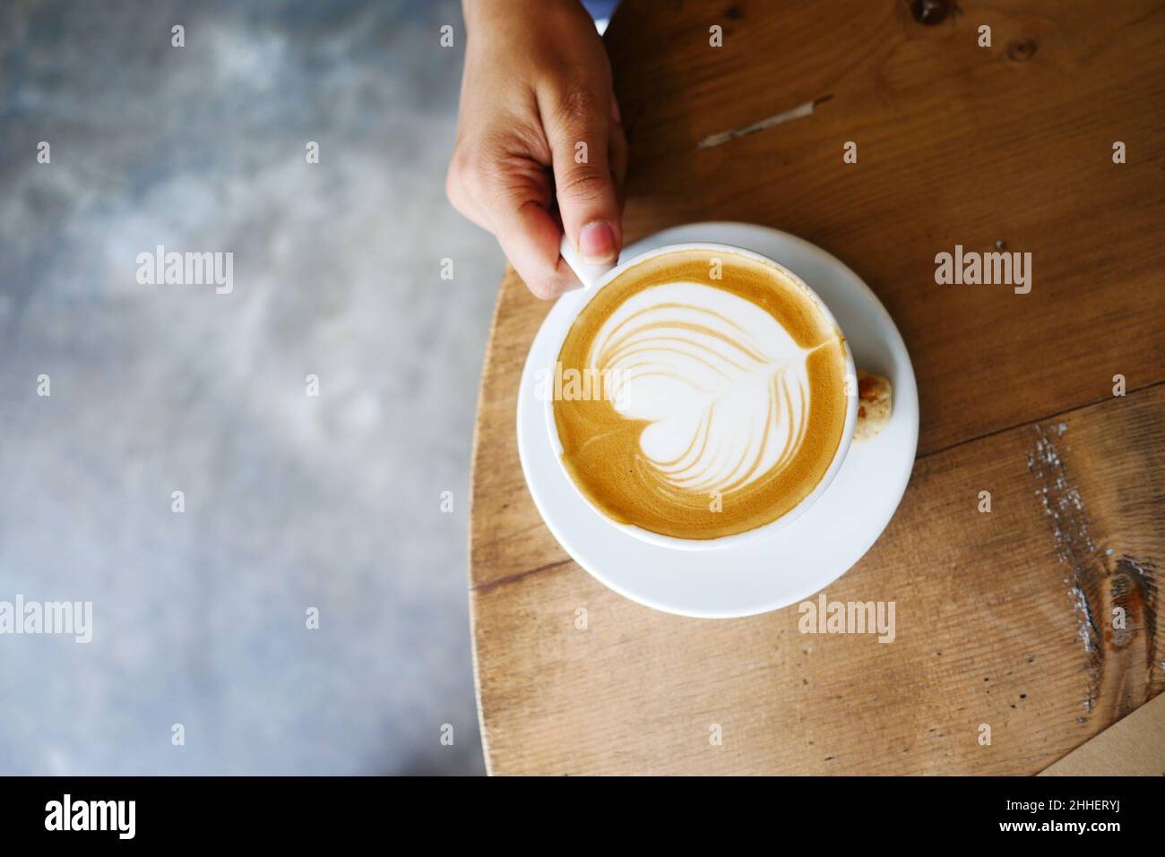 top view of a cup of late coffee with heart shape design on top on cafe ...