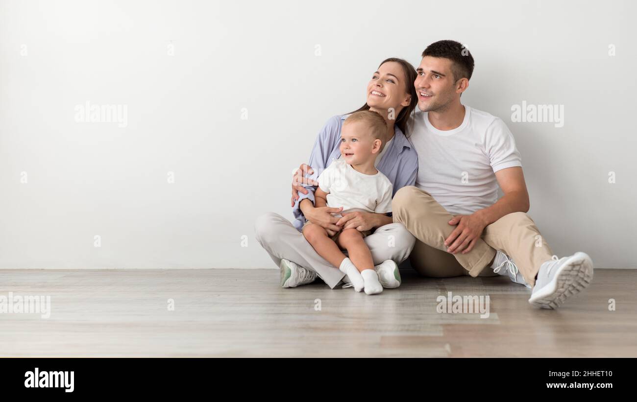 Family Offer. Happy Parents With Infant Child Sitting On Floor Looking ...