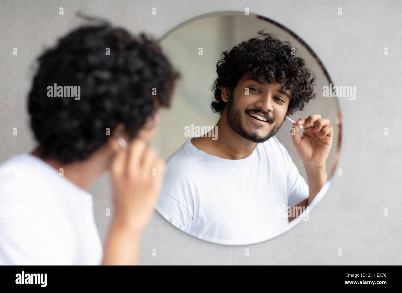 Daily hygiene routine. Indian man cleaning ears using cotton swab while ...