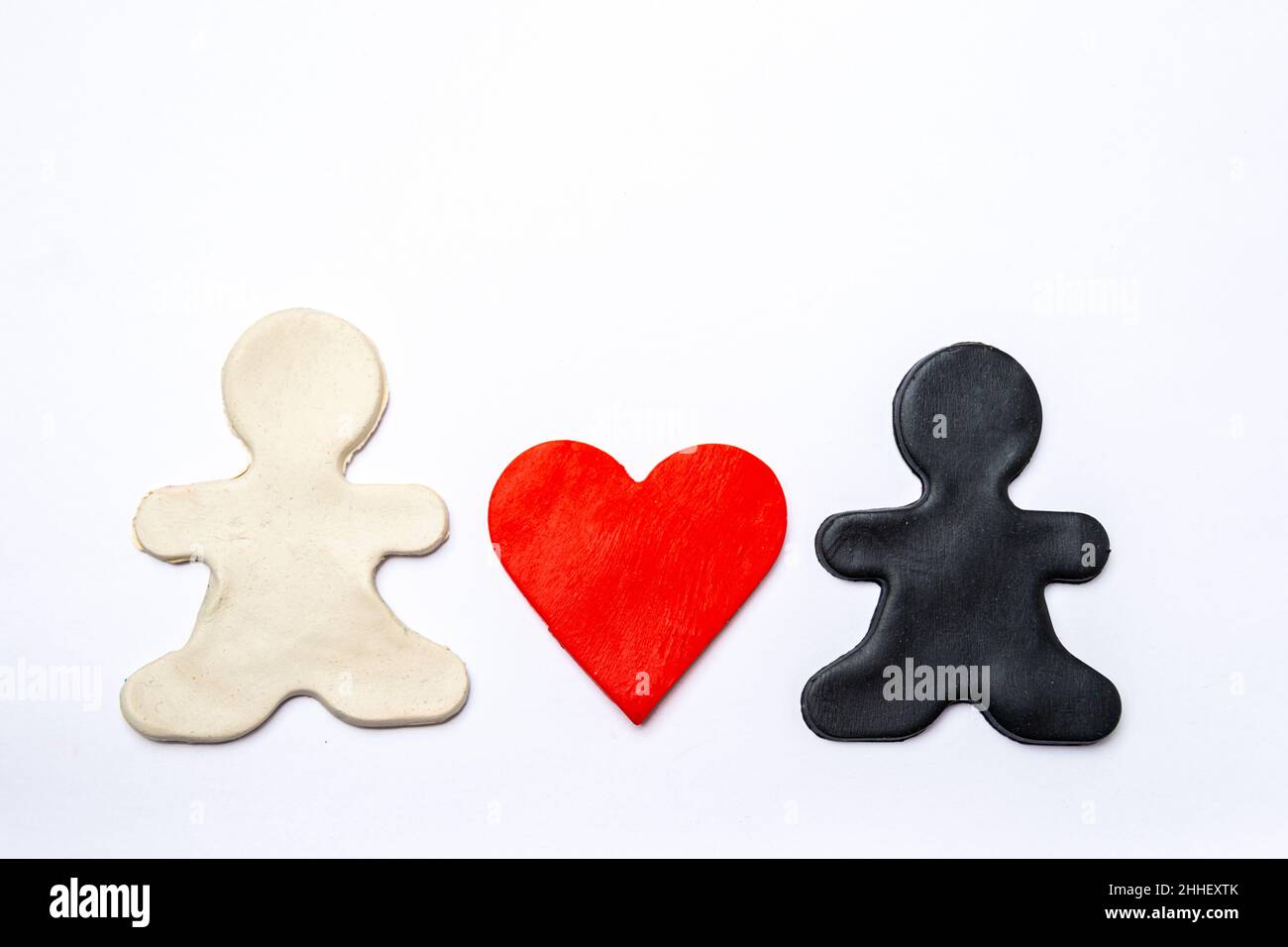 Small black and white plasticine men hold a red plasticine heart in ...