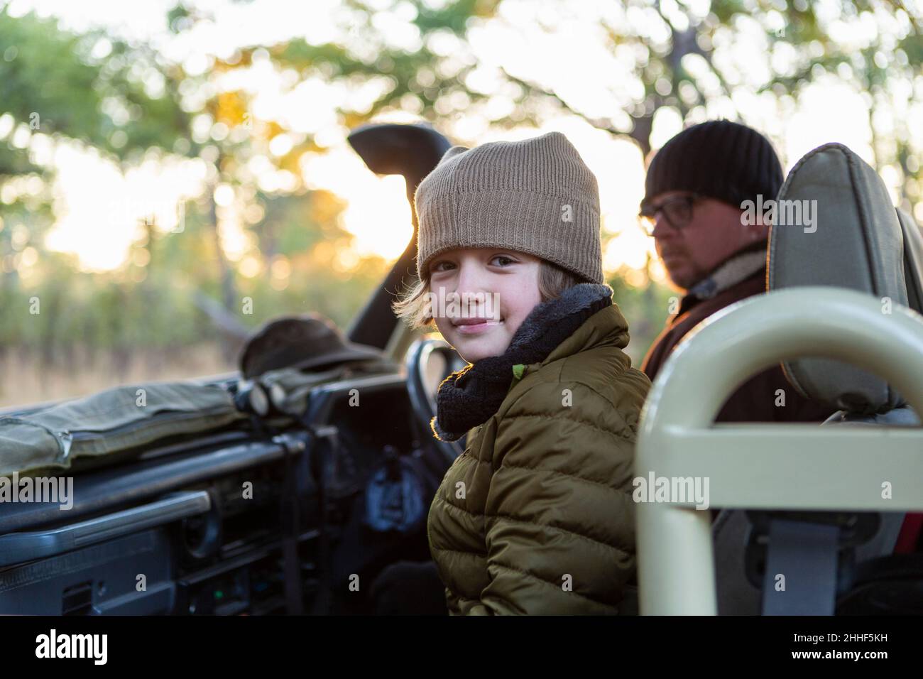 A boy in a hat and coat in a jeep at sunrise on a safari drive Stock ...