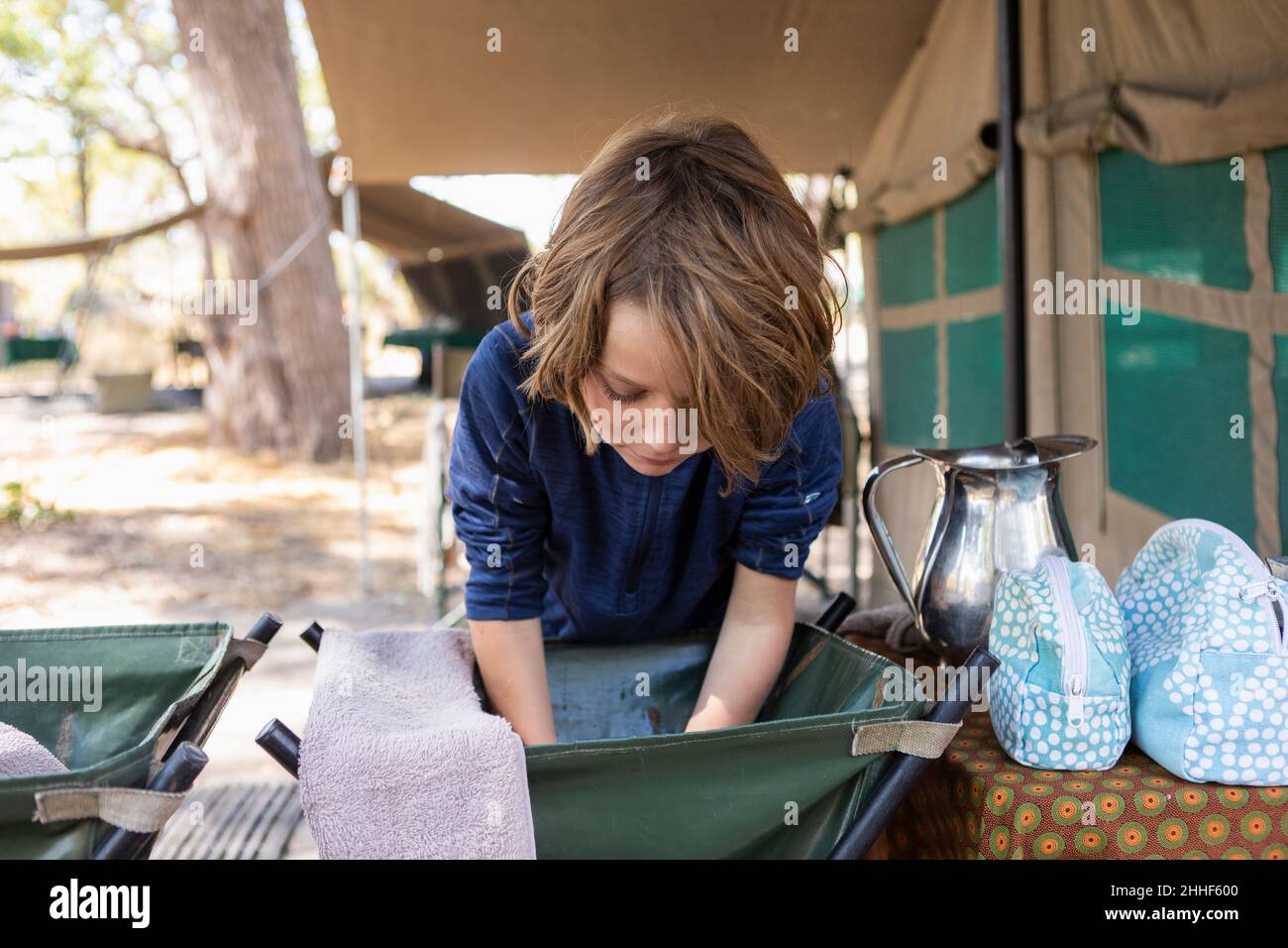 A boy washing his face in a basin at a campsite in the Okavango Stock ...