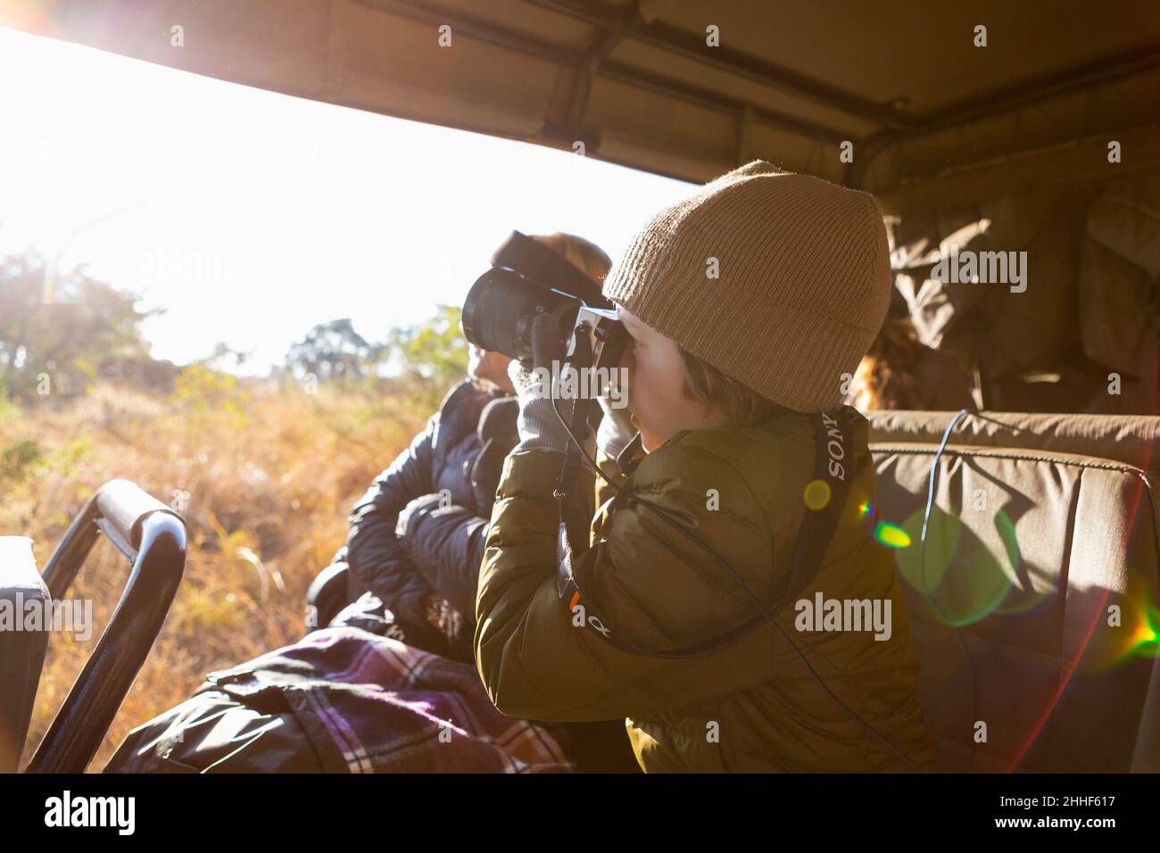 Eight year old boy with a large camera, looking out of a jeep at ...