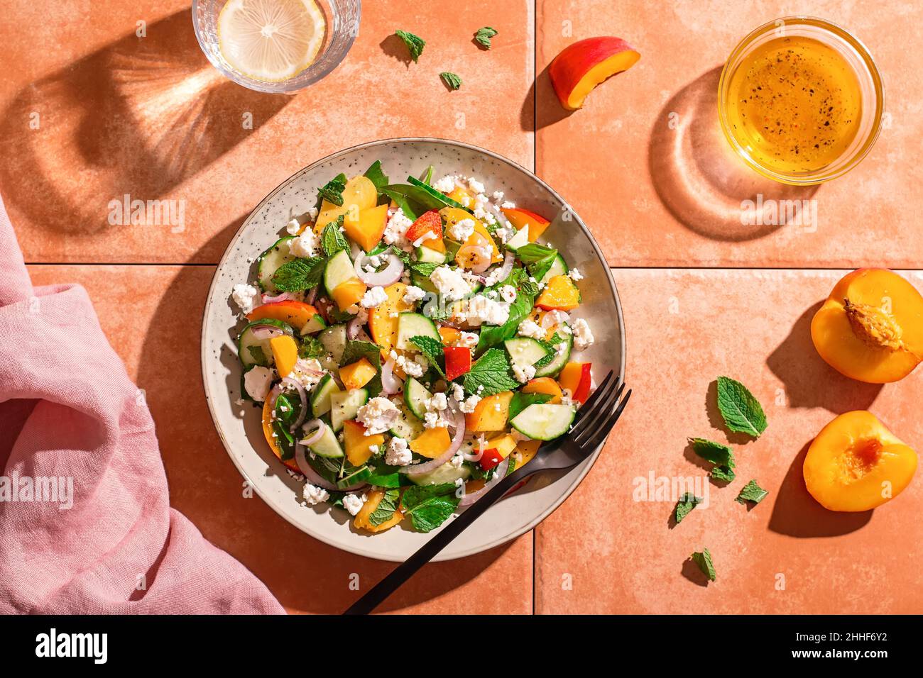 Peach and cheese salad with dressing and herbs on terracotta tile table ...
