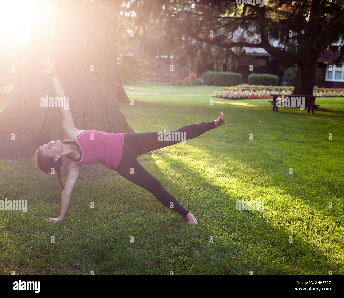 Woman balancing on side in yoga pose in park Stock Photo - Alamy