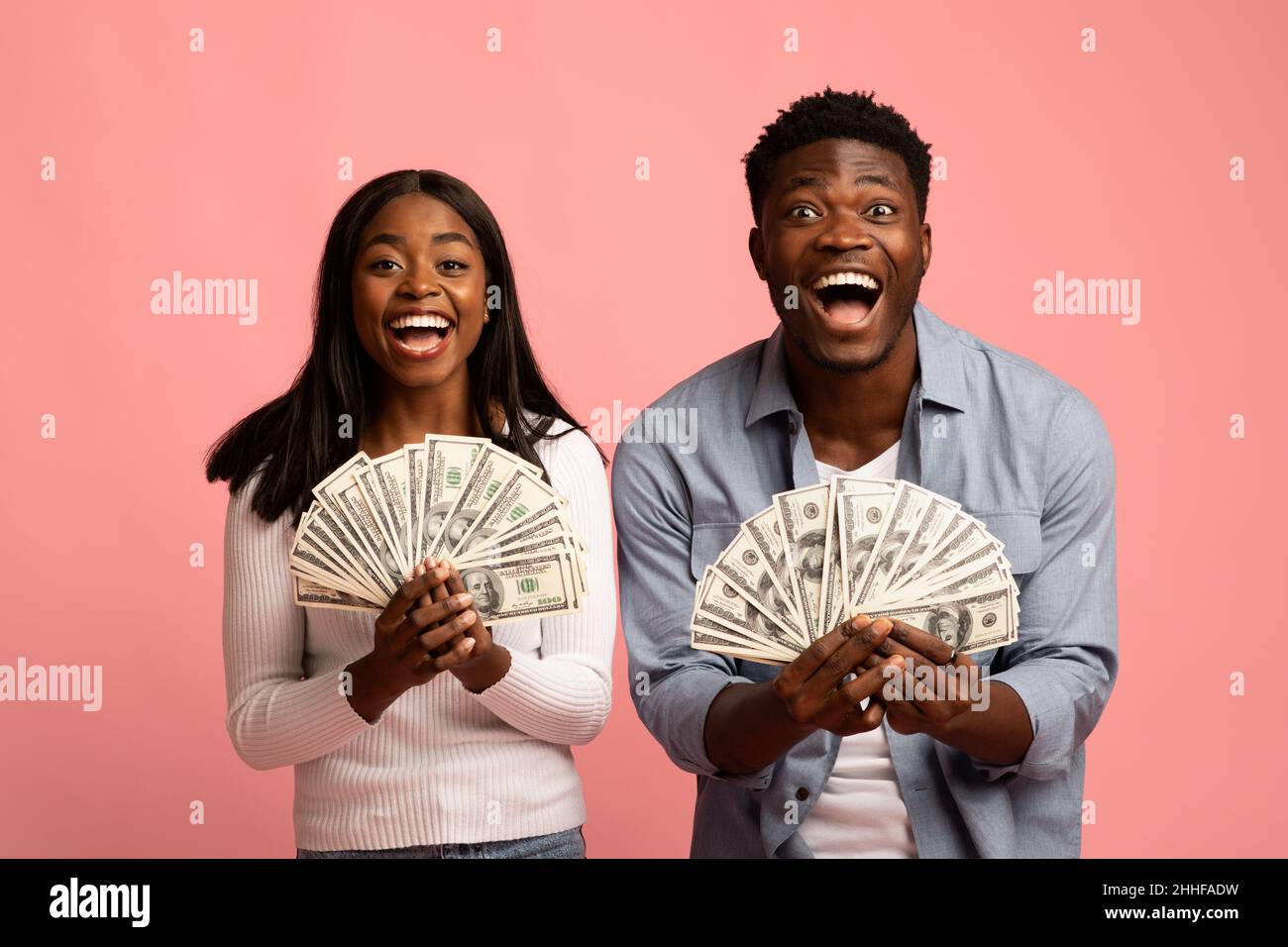 Emotional rich black couple showing cash on pink Stock Photo - Alamy