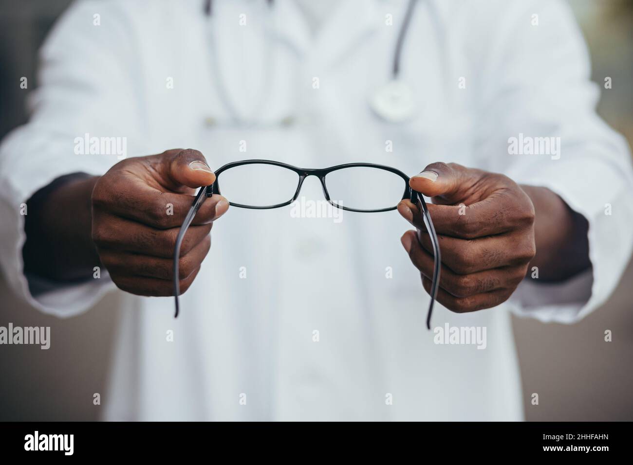 Close-up African American doctor offers glasses to patient ...