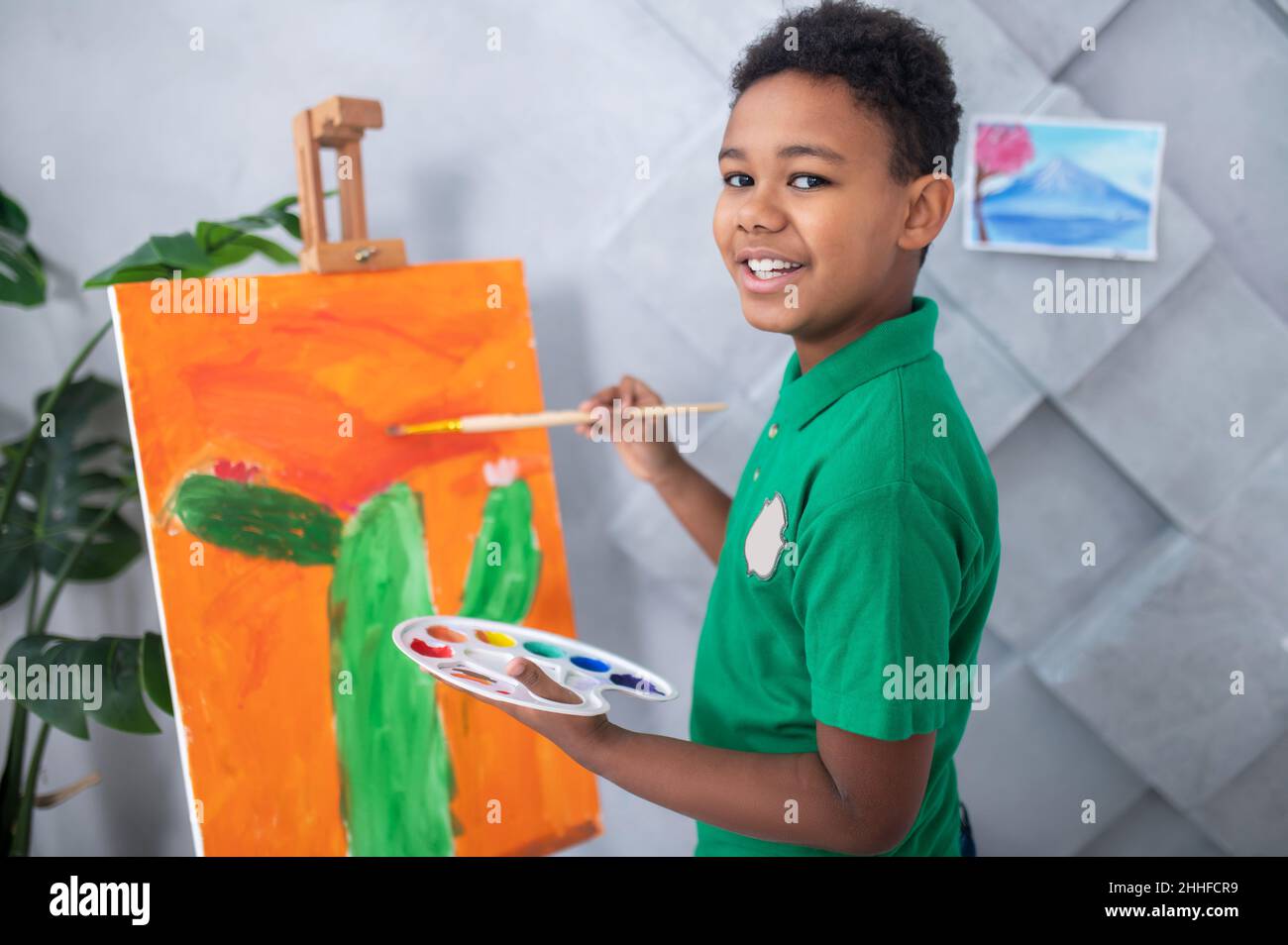 Boy painting on easel looking at camera Stock Photo - Alamy