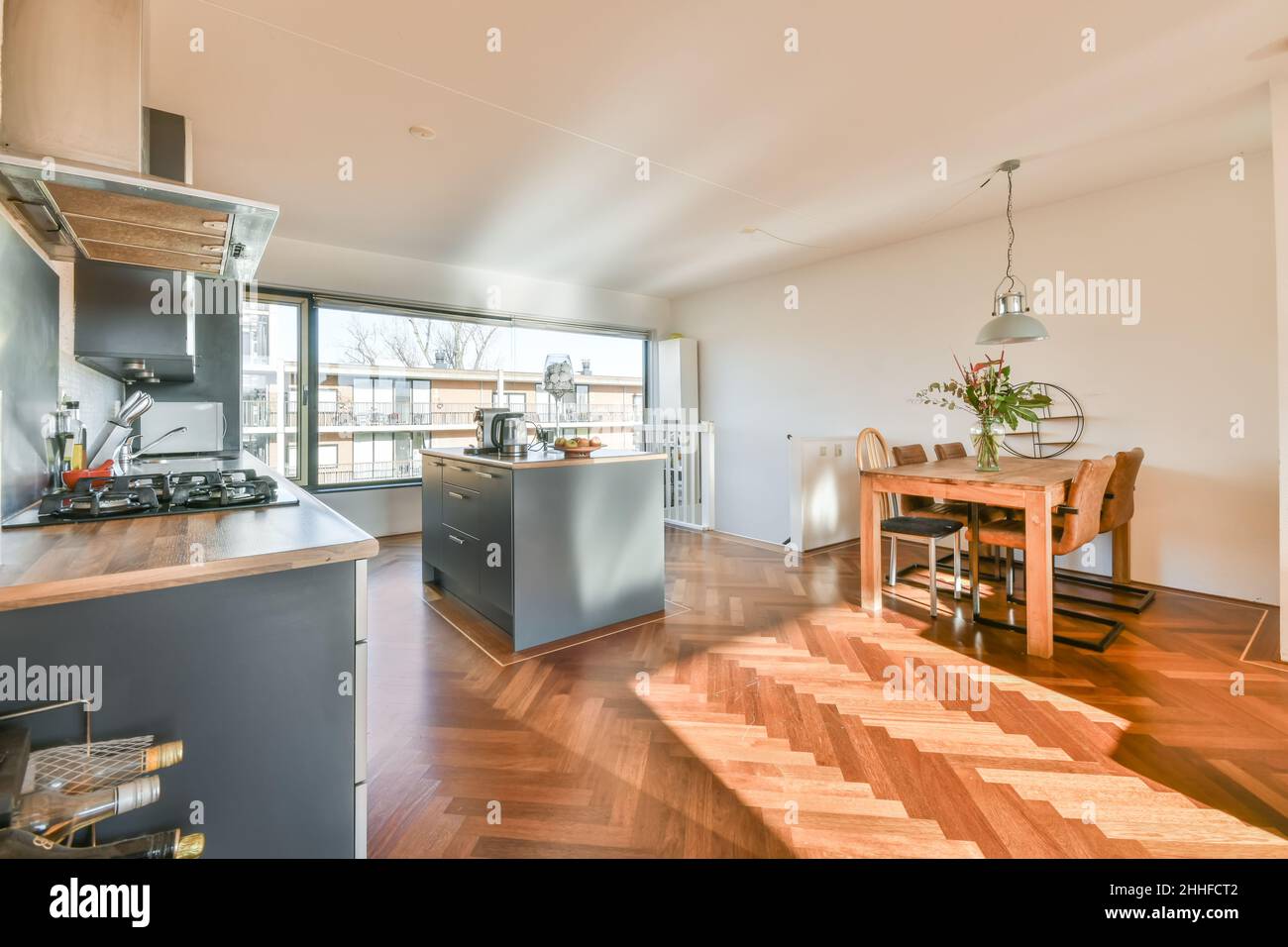Wooden table and chairs in modern kitchen with large window front in ...