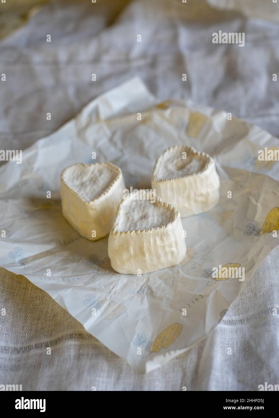 Heart-shaped cheese with white mold on wrapping paper. Home production ...