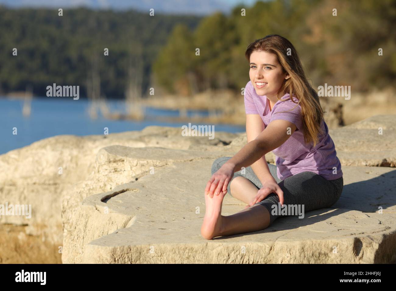 Happy sportswoman stretching leg sitting in nature after sport Stock ...