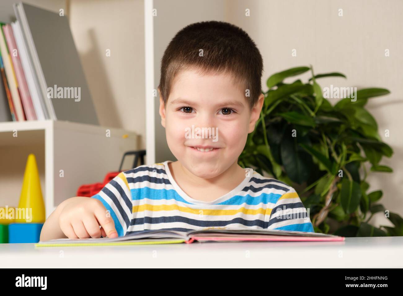 A beautiful happy child of 4 years old learns to read, sits in front of ...