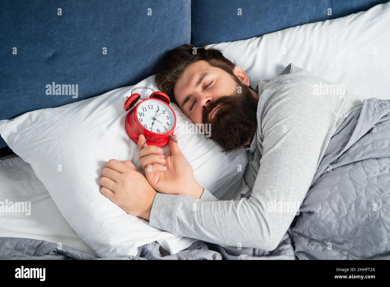 Guy sleeping with alarm clock in bed, sleep time Stock Photo - Alamy