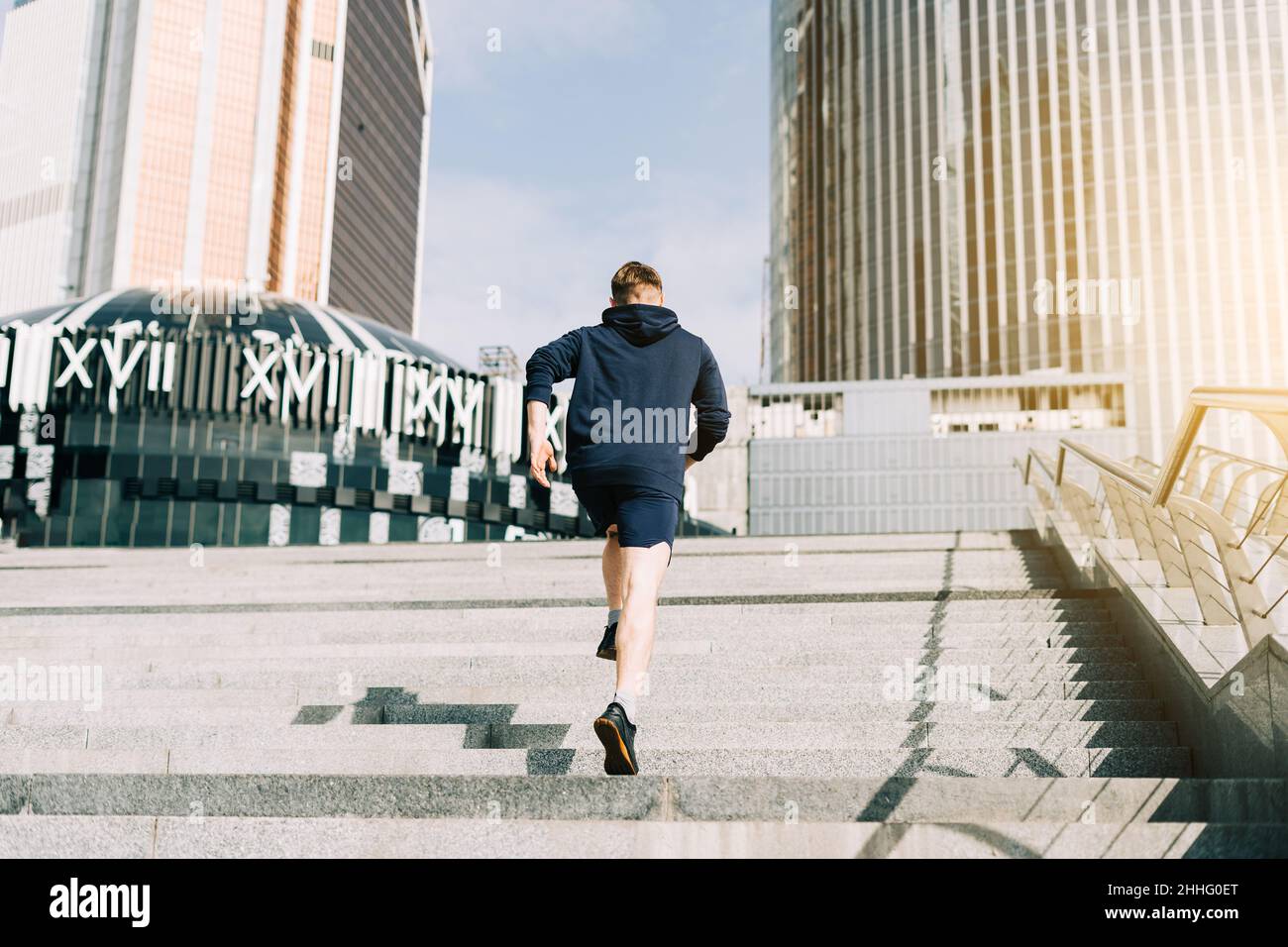Young athlete man runner running up and down on city stairs in summer ...