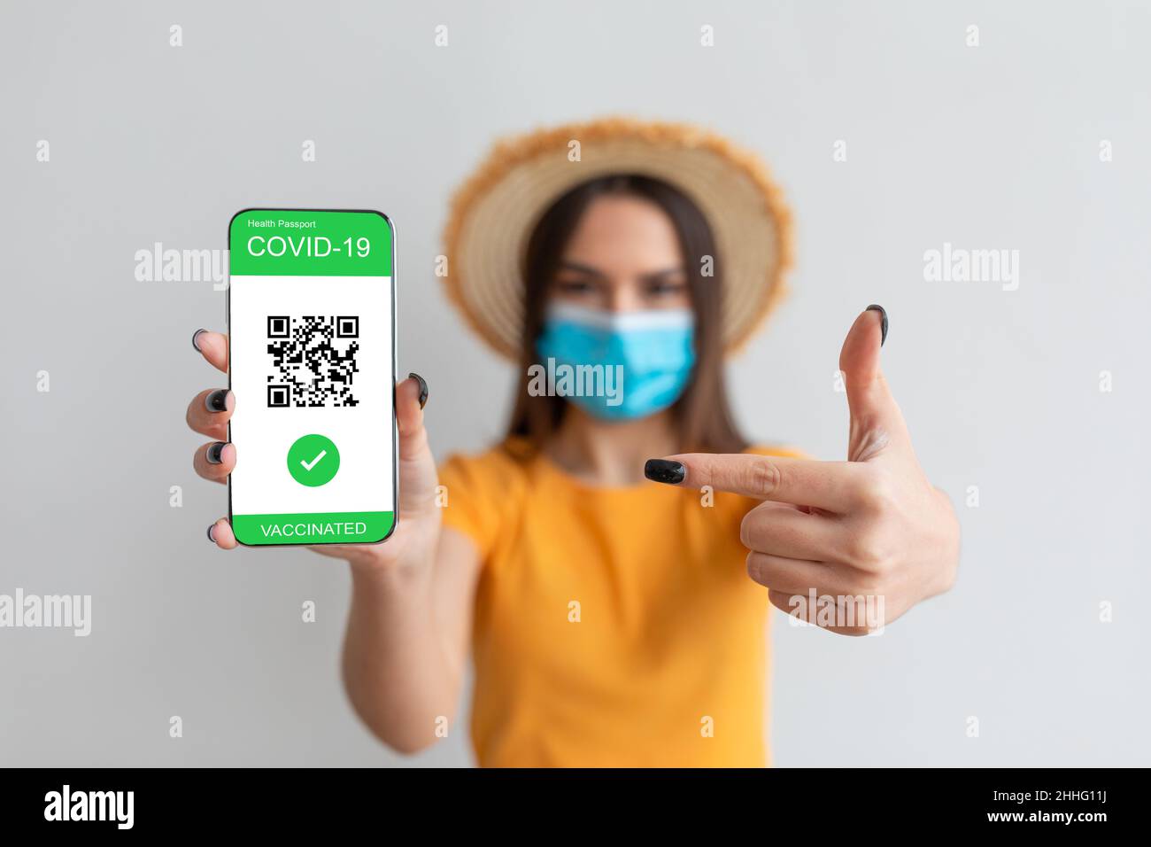 Woman pointing at smartphone with digital covid-19 vaccination ...