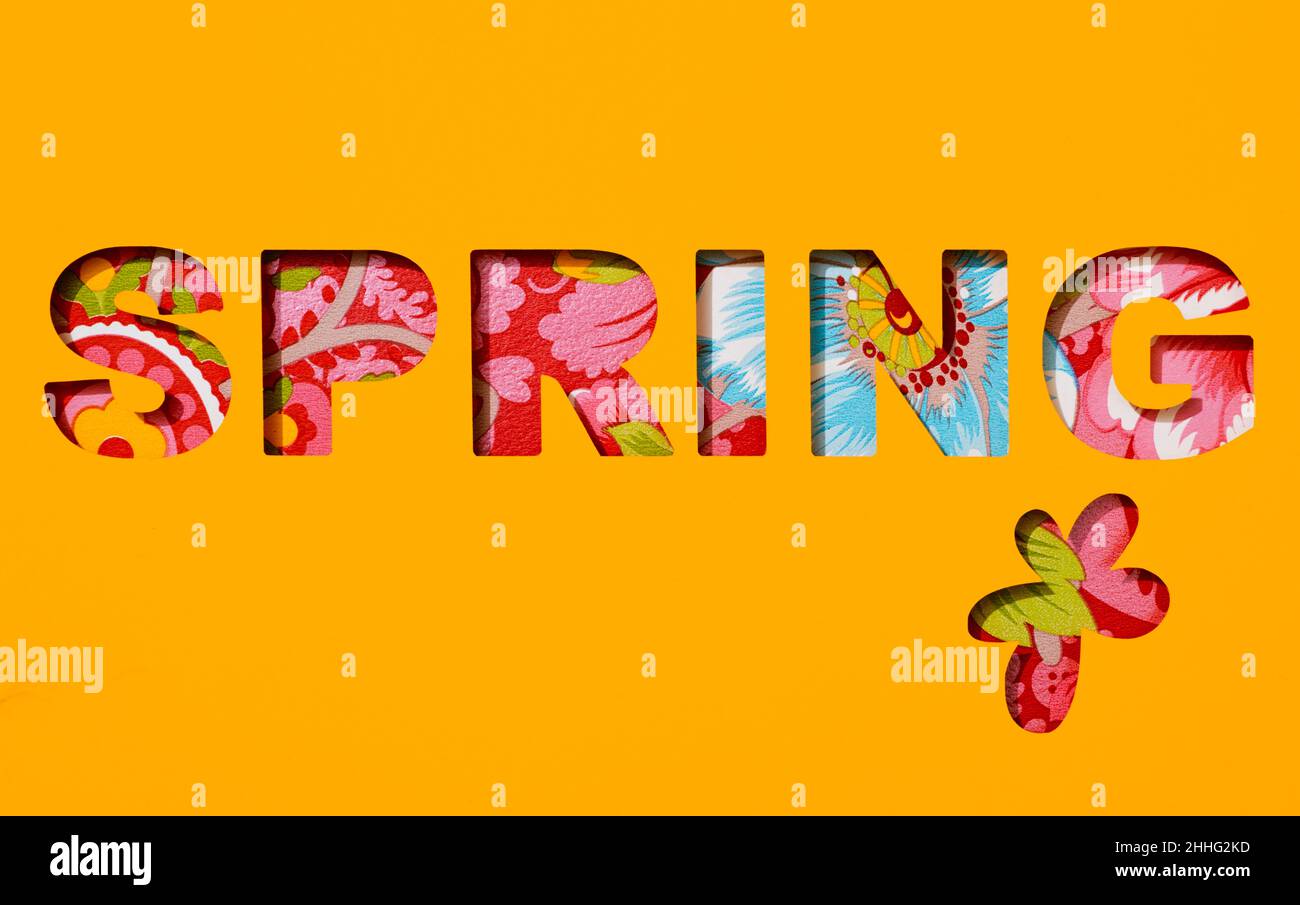 the text spring and a flower cut out on an orange paper, and a floral ...