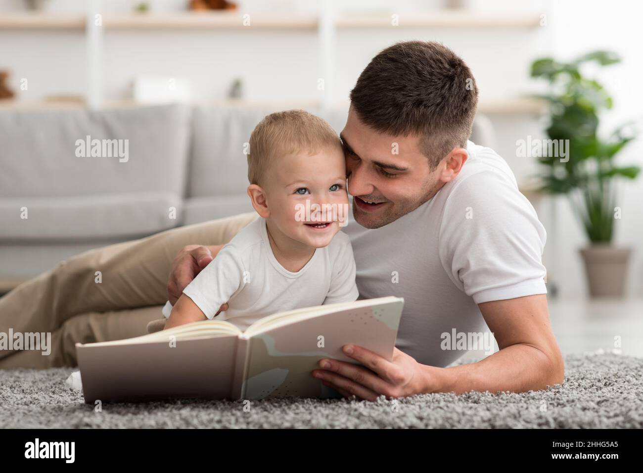 Portrait Of Caring Young Dad Reading Book To Happy Baby At Home Stock ...