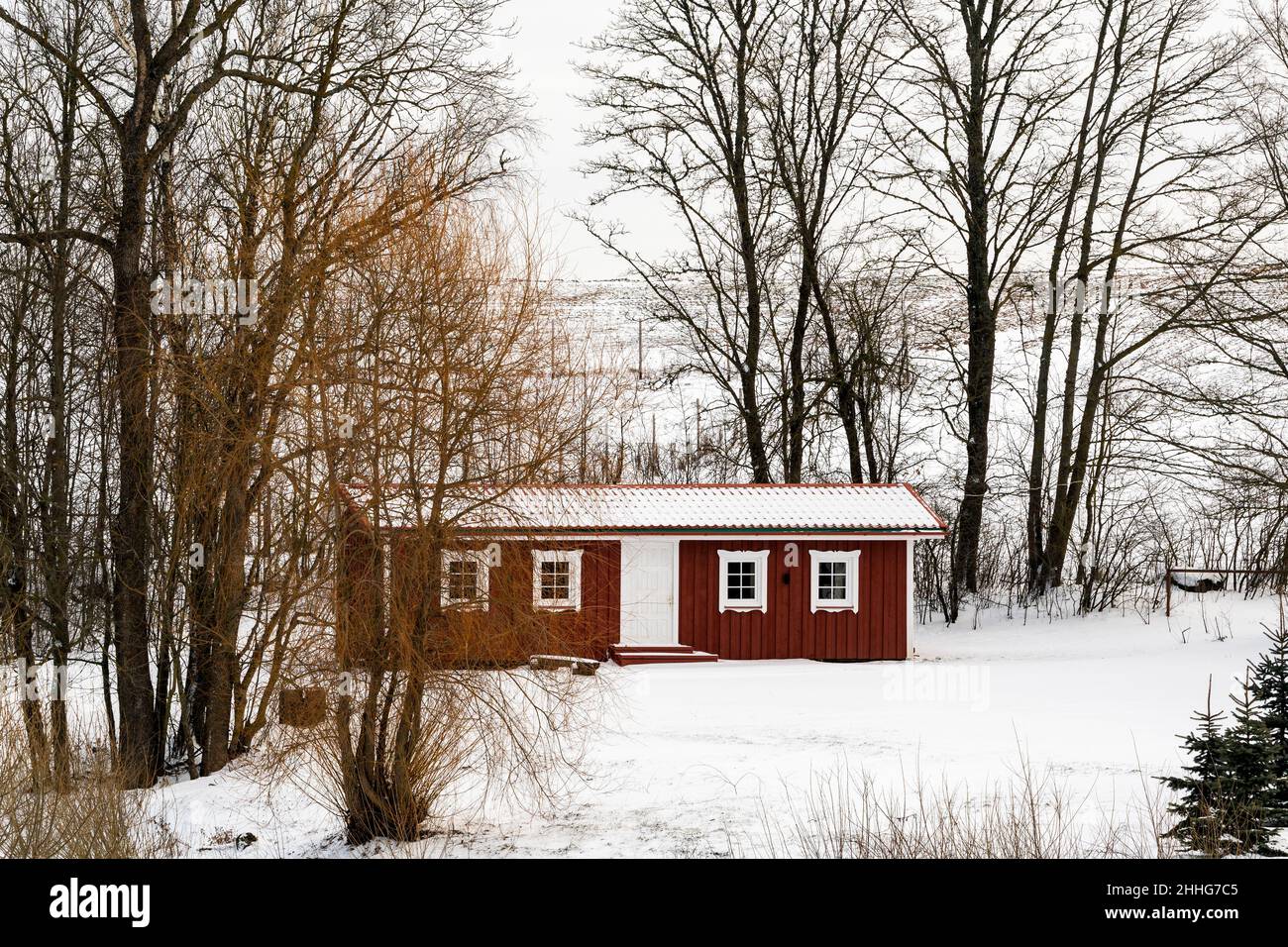 A small red house in the forest. Farm barn in a cold Winter landscape ...