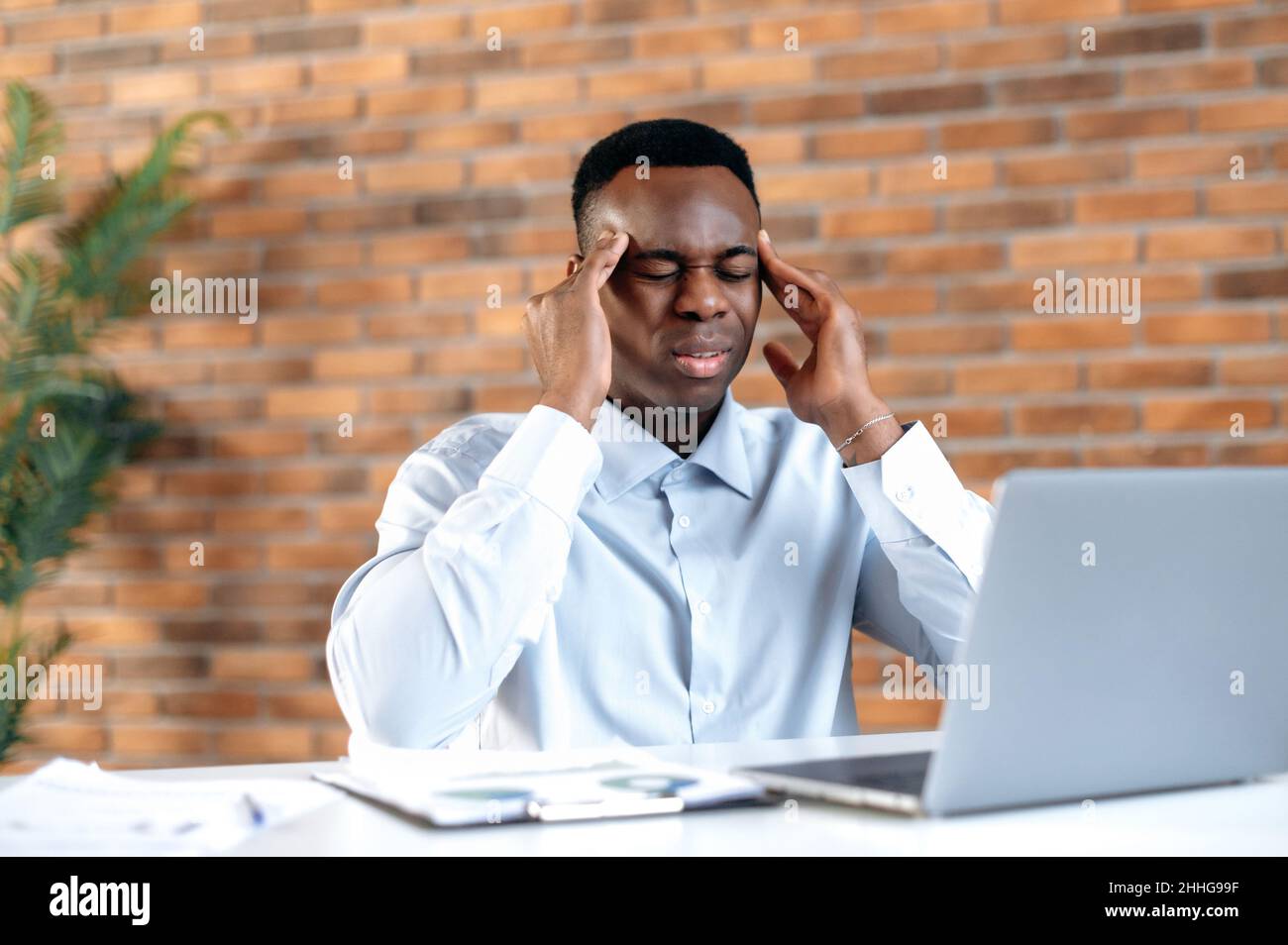 Overworked exhausted young adult African American man, manager or ...