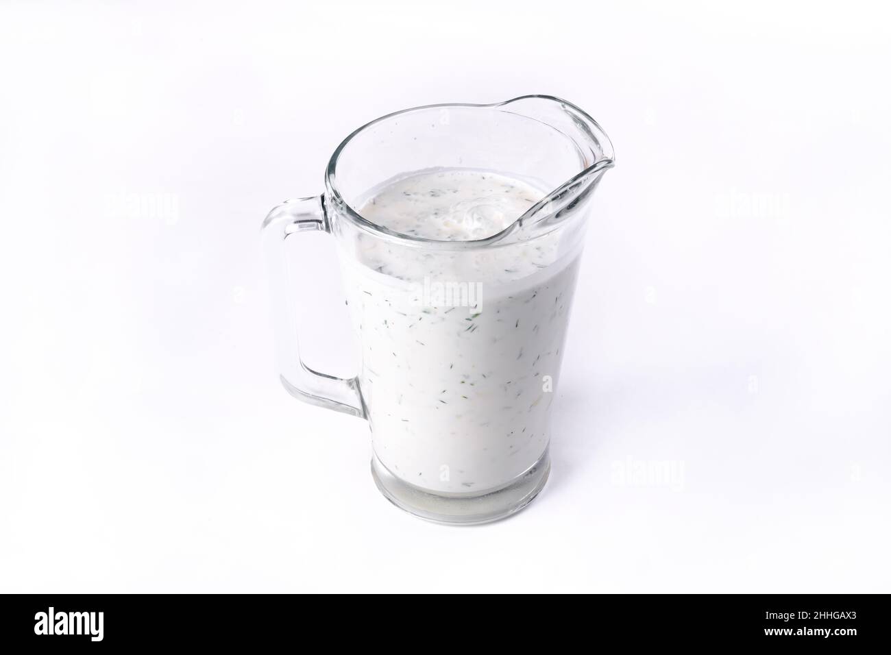 A glass of ayran with dill and parsley, highlighted on a white isolated ...