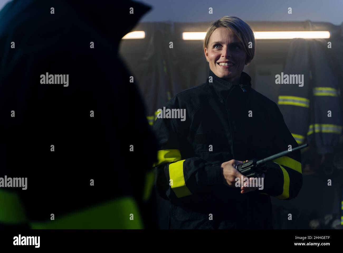 Happy mid adult female firefighter with walkie talkie in fire station ...