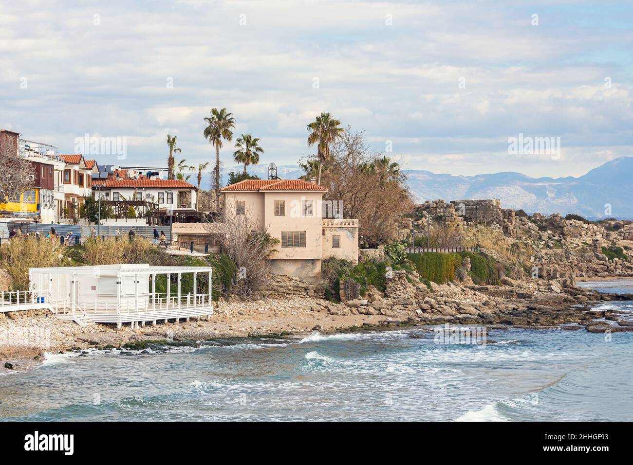 Old stone ancient houses full of green plants, cafe on the seashore in ...