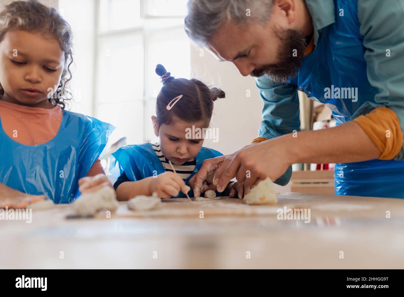 Little kids with teacher working with pottery clay during creative art ...